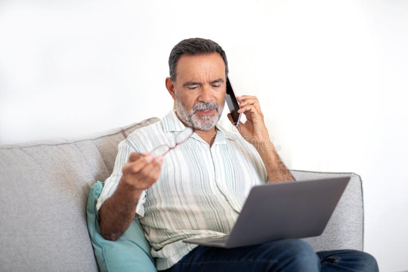 Senior Man Talking on Phone Solving Problems with Laptop Indoors Stock ...