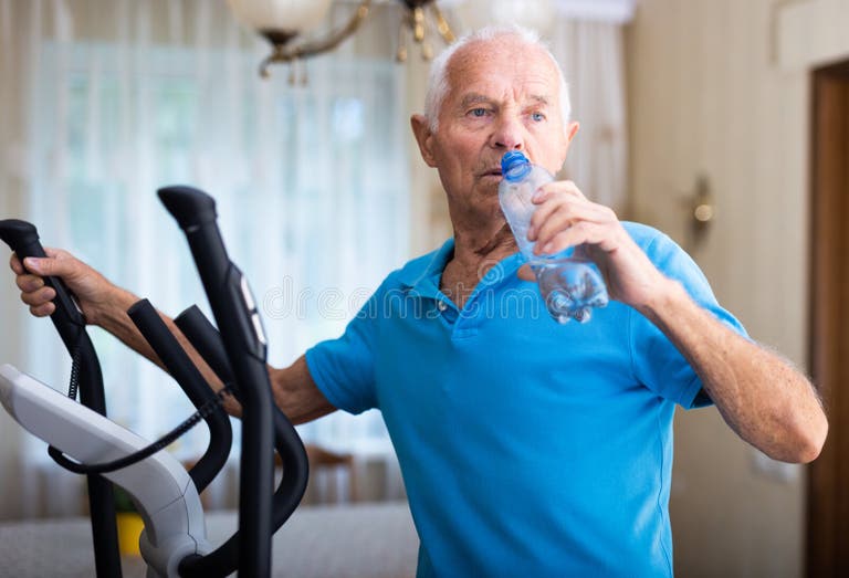 Senior Man Using Elliptical Trainer and Drinking Water Stock Image ...