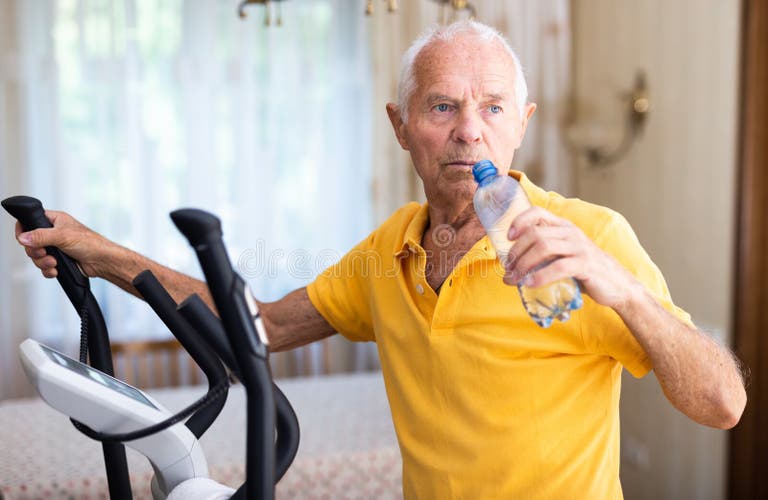 Senior Man Using Elliptical Trainer and Drinking Water Stock Image ...