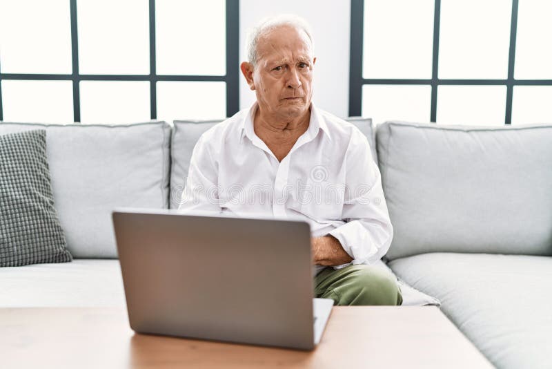 Senior Man Using Laptop at Home Sitting on the Sofa Depressed and Worry ...
