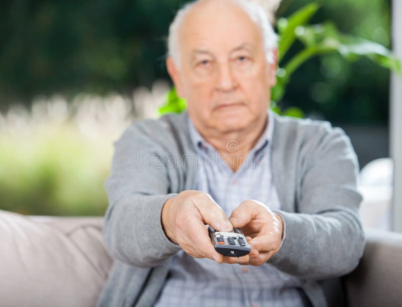 Senior Man Using Remote Control while Sitting on Stock Photo - Image of ...