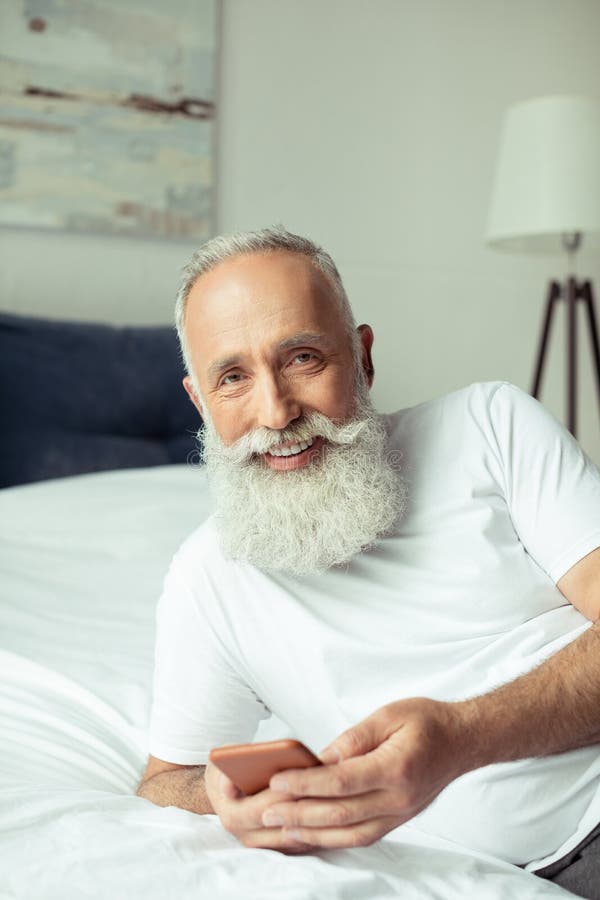 Senior Man Using Smartphone while Lying on Bed Stock Image - Image of ...