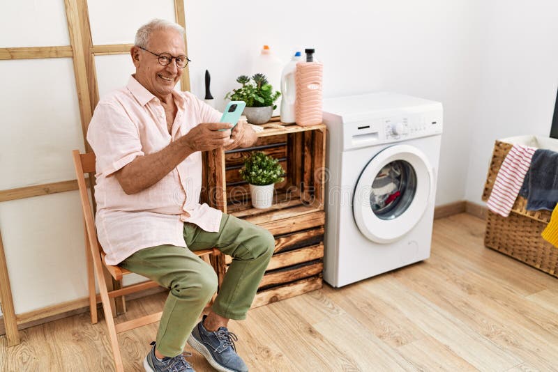 Senior Man Using Smartphone Waiting for Washing Machine at Laundry Room ...