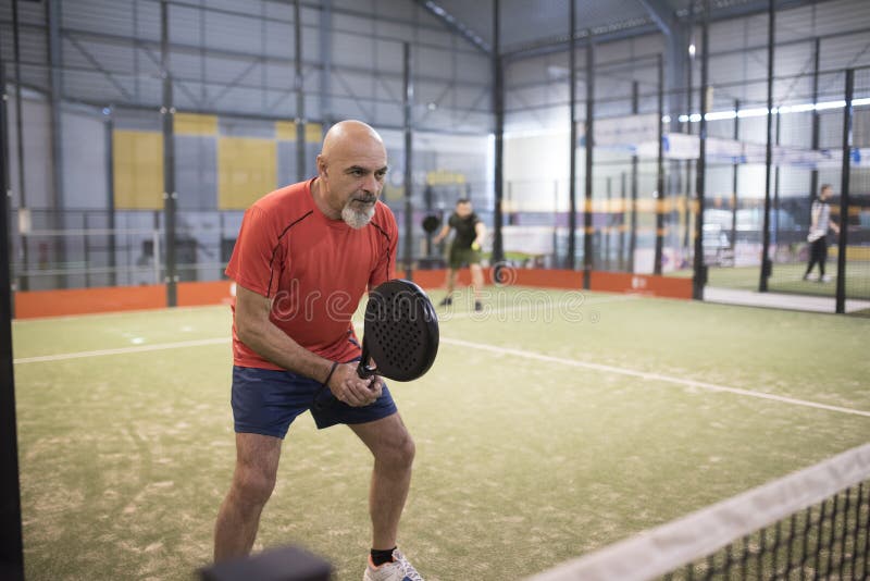 Senior Mann Und Ihr Sohn Spielen Paddle Tennis Auf Dem Platz, Dienen ... Senior Mann Und Ihr Sohn Spielen Paddle Tennis Auf Dem Platz, Dienen ...