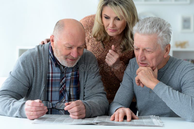 Senior People Sitting at Table and Reading Newspaper Stock Photo ...