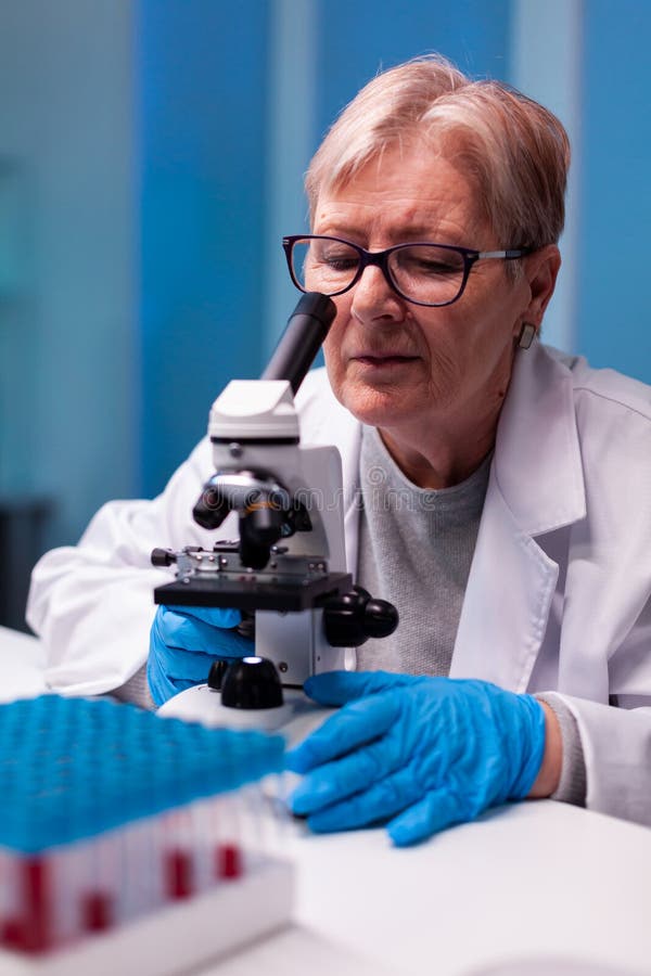 Senior Scientist Looking through Microscope at Sample in Biology Lab ...