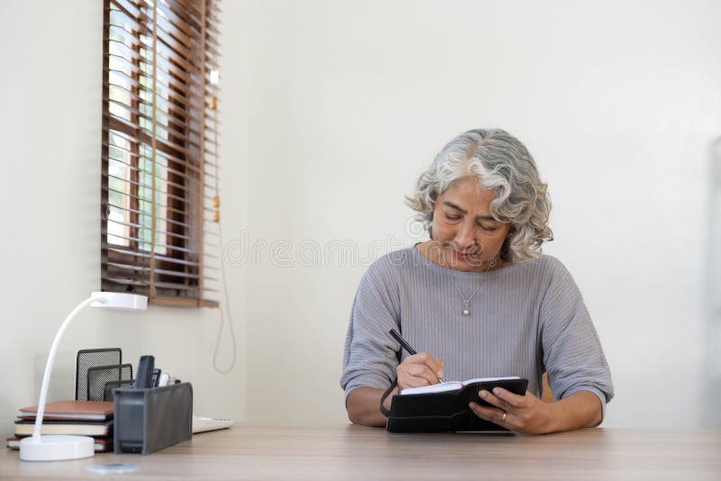 Senior Stylish Woman Taking Notes in Notebook while Using Laptop at ...