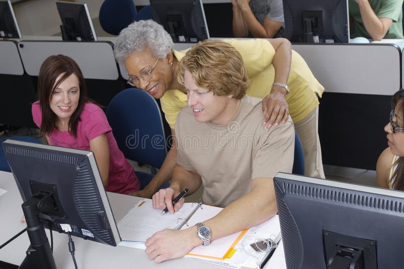 Teacher Assisting College Student on Computers Stock Image - Image of ...