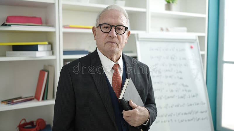Senior Teacher Standing Serious Holding Book at University Classroom ...