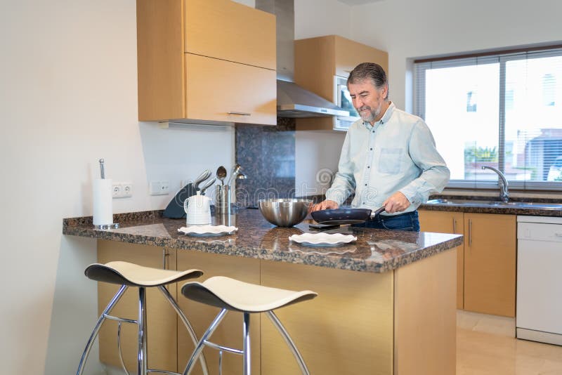 Senior White Man Cooking with a Pan in Hand in the Kitchen at Home ...
