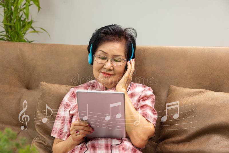 Senior Woman is Listen Music Via Computer Tablet on Sofa at Home. Stock ...
