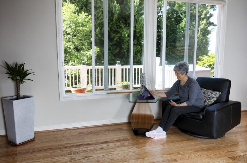 Senior Woman Looking at Her Computer while at Home Near the Backyard ...