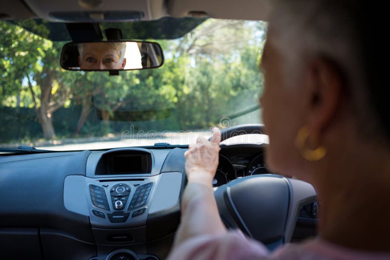 Senior Woman Looking into Rear View Mirror while Driving a Car Stock ...