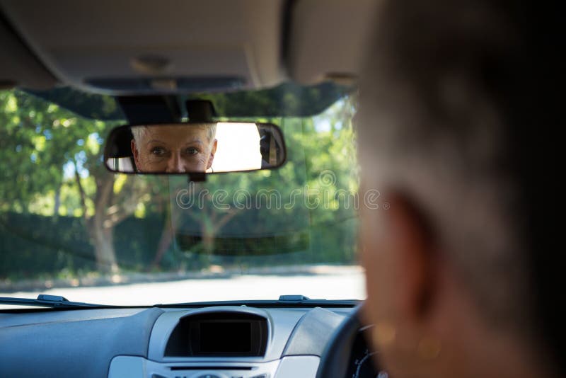 Senior Woman Looking into Rear View Mirror while Driving a Car Stock ...