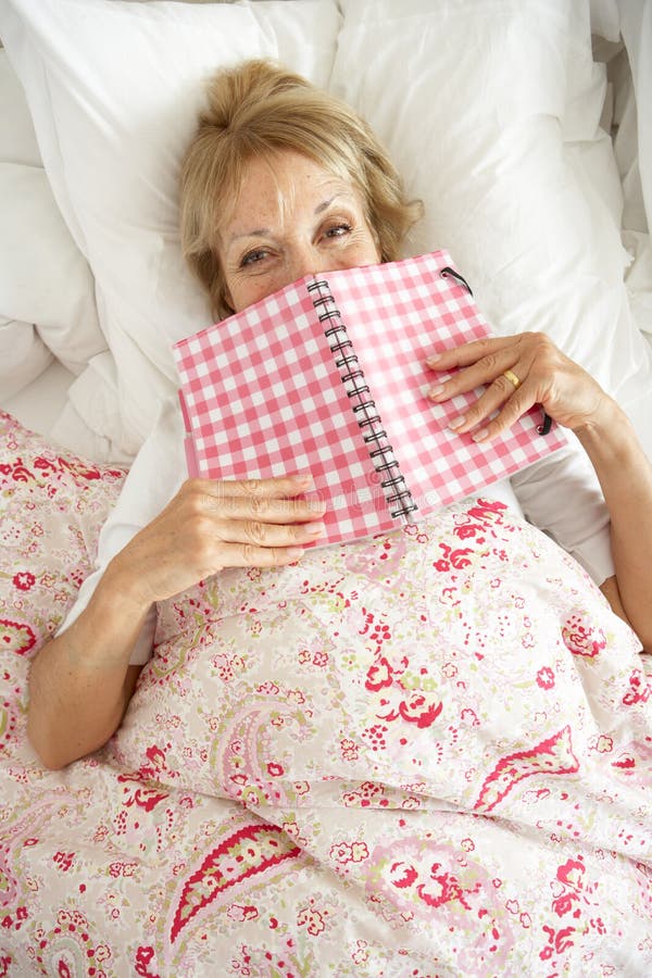 Senior Woman Relaxing in Bed Reading Diary Stock Photo - Image of ...