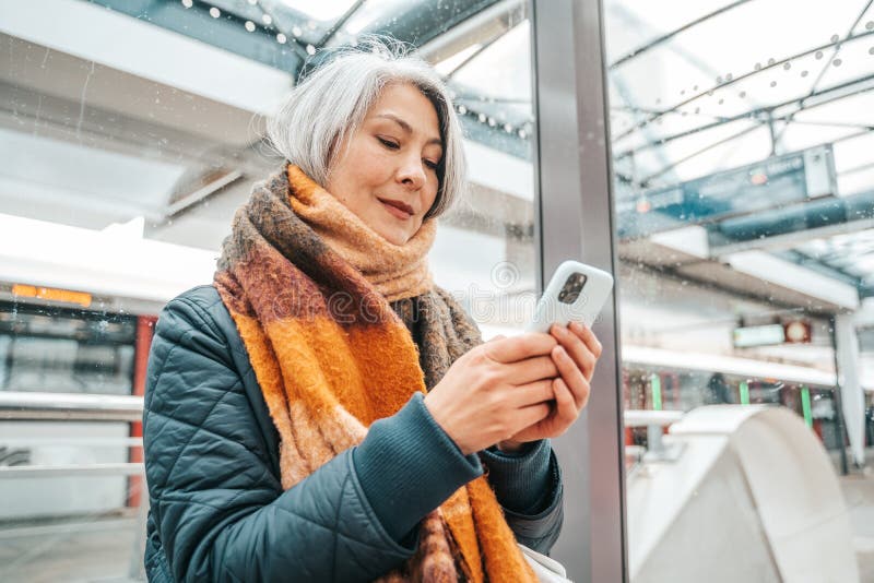 Senior Woman Send Message with a Mobile Phone and Waits for a Train ...