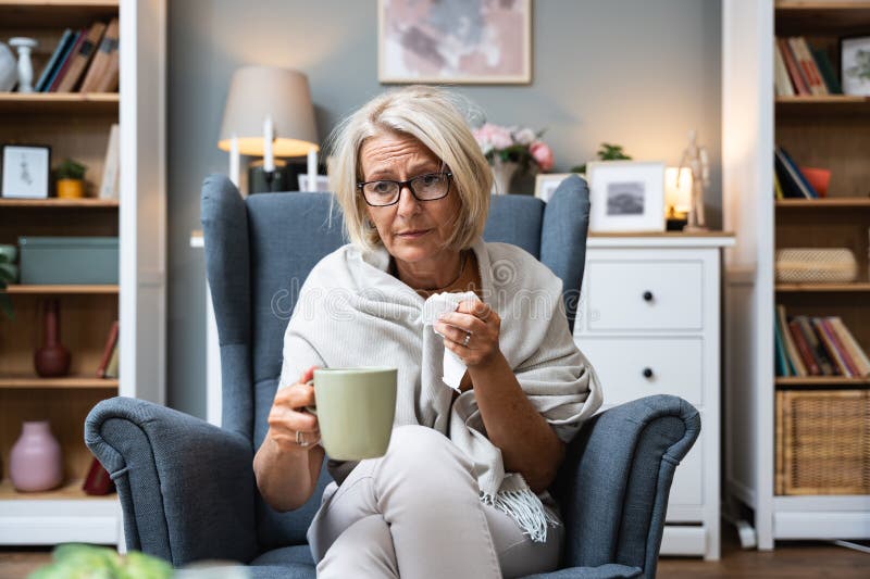 Senior Woman Sick And Blowing Nose At Home From Virus Allergy And