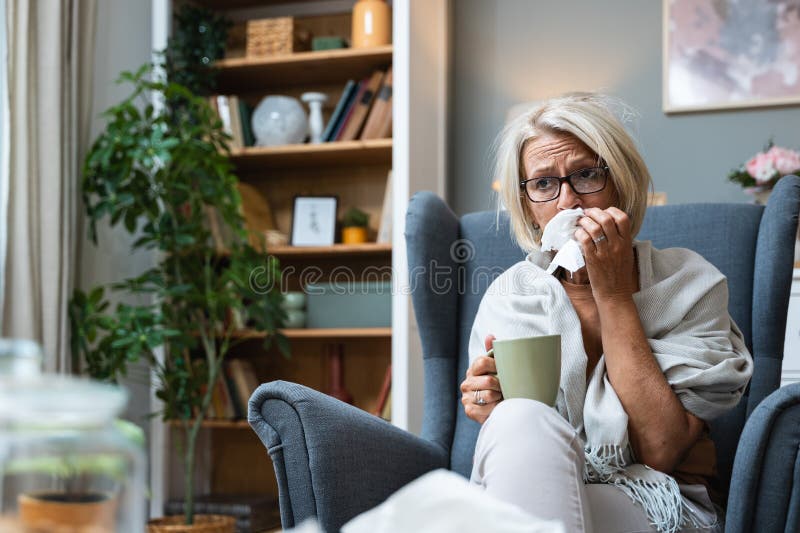 Senior Woman Sick And Blowing Nose At Home From Virus Allergy And