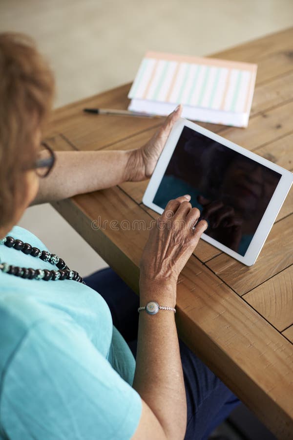 Senior Woman Sitting at Table Using Tablet Computer, Elevated Over ...