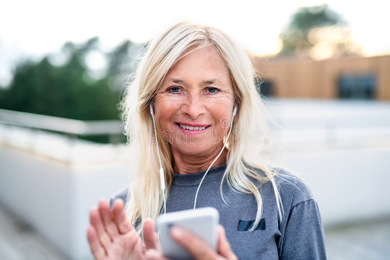 A Senior Woman with Smartphone Outdoors Resting after Exercise. Stock ...