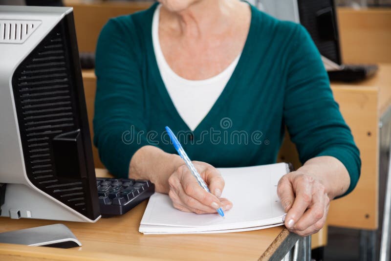 Senior Woman Writing Notes in Computer Class Stock Image - Image of ...