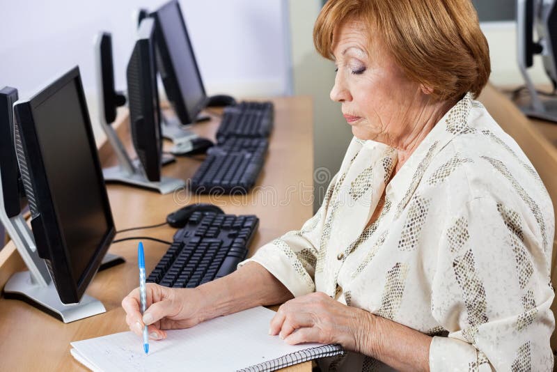 Senior Woman Writing Notes in Computer Class Stock Photo - Image of ...
