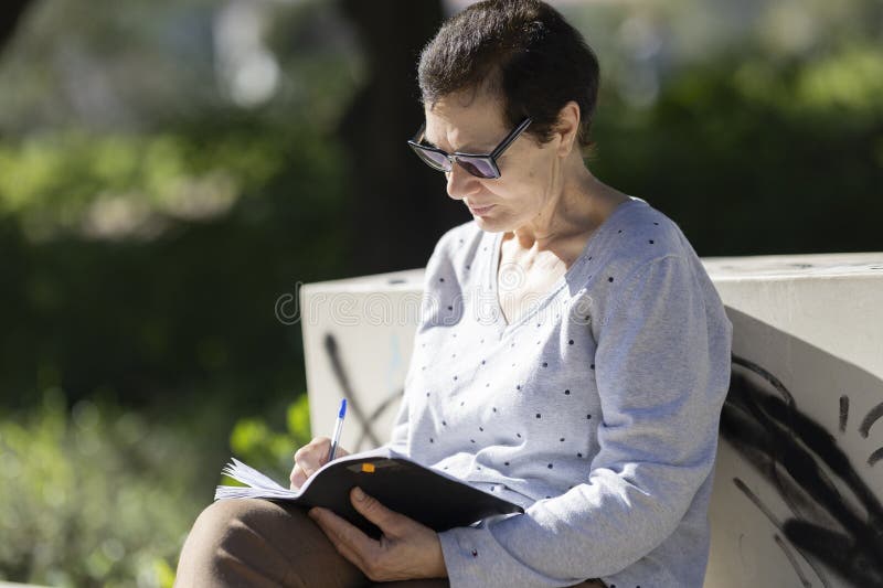 Senior Woman Writing Notes in Notebook Outdoors Stock Photo - Image of ...