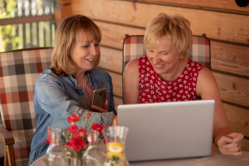 Senior Women Laugh Together Using and Looking at Laptop, at Home Stock ...