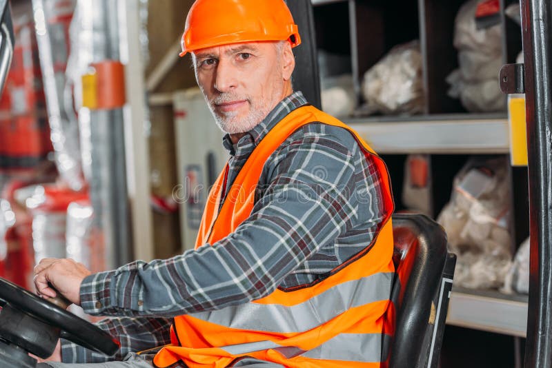 Senior Worker in Safety Vest and Helmet Sitting in Forklift Machine ...