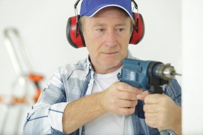 Senior Workman Using Drill and Wearing Ear-defenders Stock Image ...