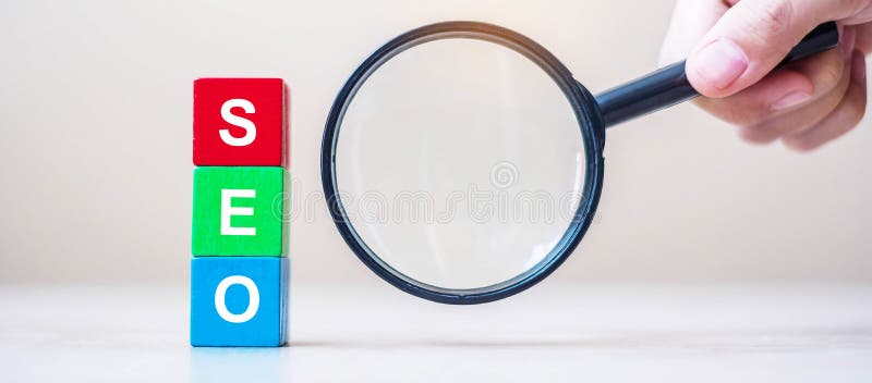 SEO Search Engine Optimization Text Wooden Cube Blocks and Hand Holding Magnifying Glass on ...