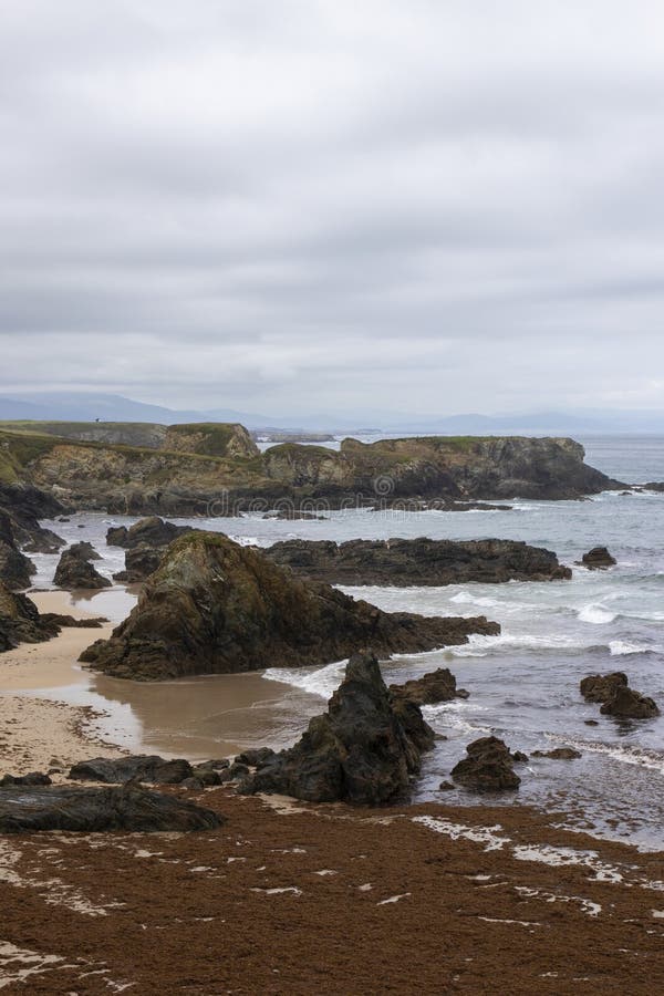 Serene Coastal Landscape: Rocky Beach Under a Cloudy Sky Stock Image ...