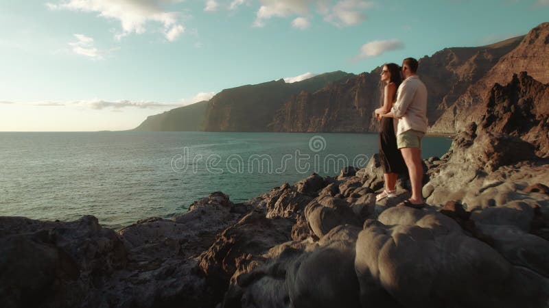 In a Serene Coastal Setting, a Couple Embraces on Rocky Terrain ...
