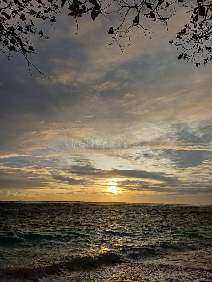 Serene Ocean Sunrise with Soft Light Breaking through the Clouds. Calm Waves Meet the Sandy ...