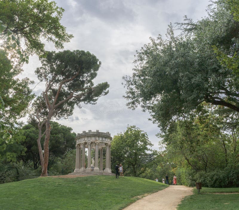 A Serene Park Scene with a Classical Rotunda and People Walking on a ...