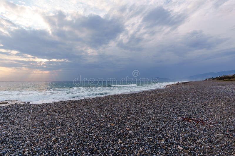 Serene Pebble Beach at Sunset with Radiant Sky and Ocean Waves Stock ...