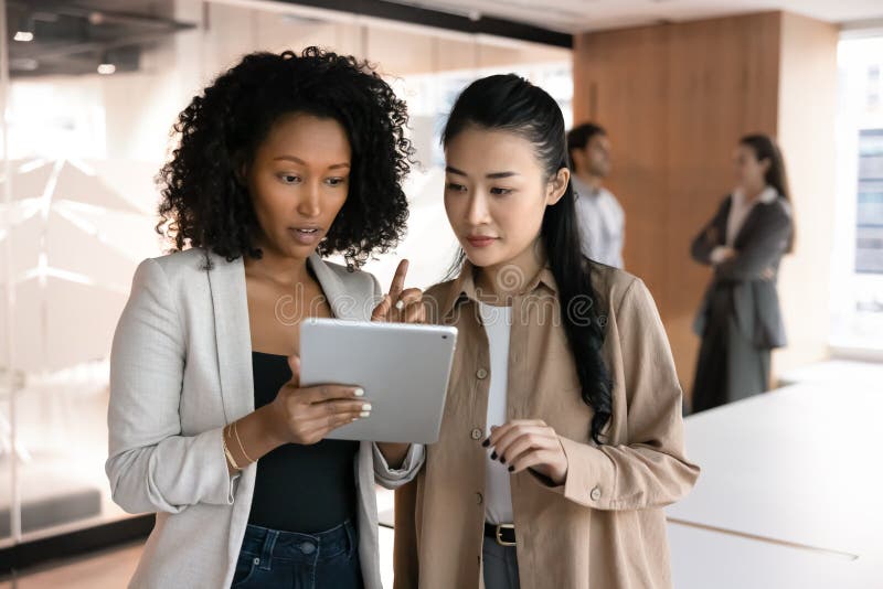 Serious African and Vietnamese Women Teammates Using Tablet in Office ...