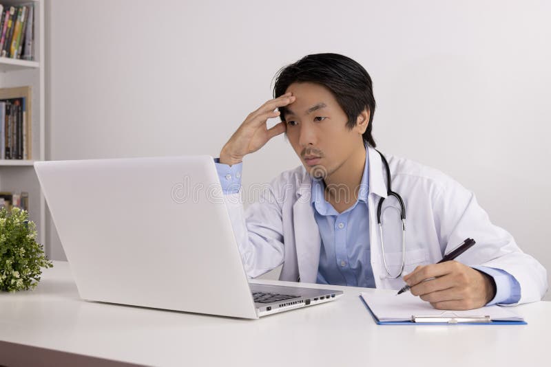 Serious Asian Doctor and Stethoscope Write Report and Using Laptop ...