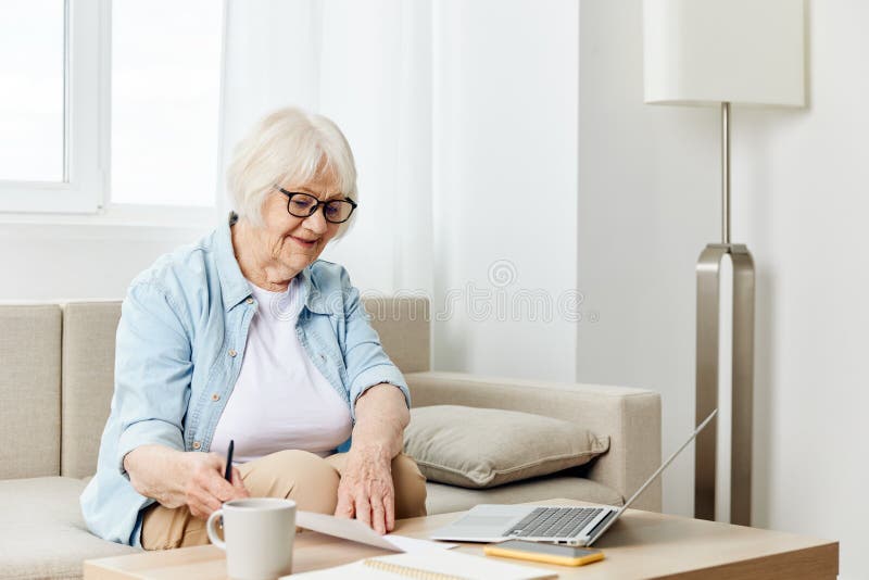 A Serious, Attentive Elderly Woman is Sitting Working from Home on a ...