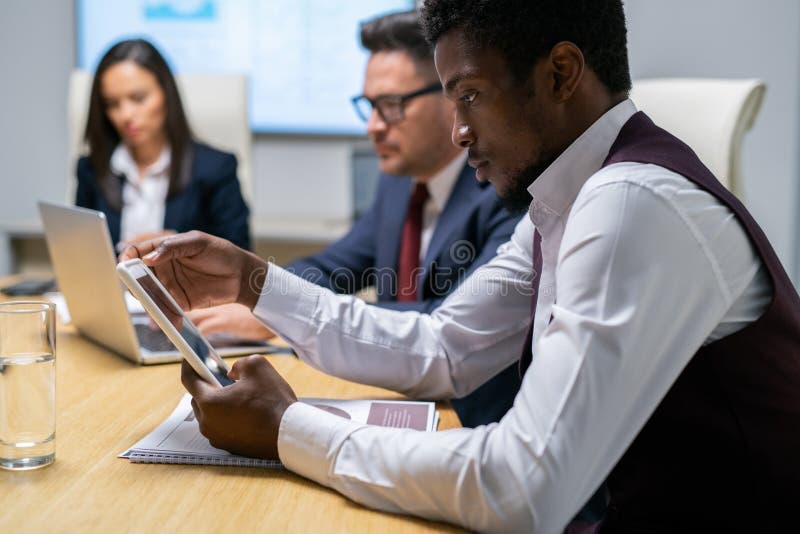 Serious Businessman Scrolling in Tablet Against Co-workers Stock Photo ...