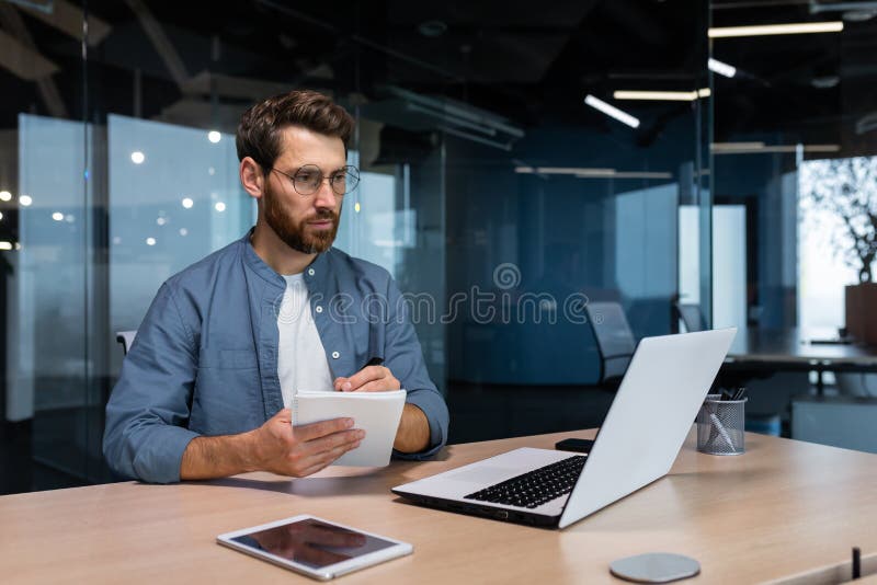 Serious Businessman is Writing Down Information Studying Online while ...