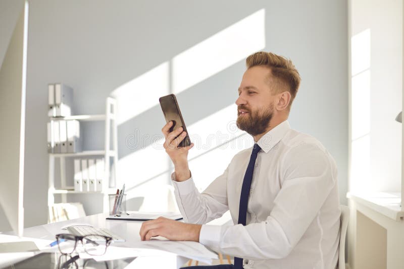 Serious Busy Businessman Reads Message on the Phone at a Table with a ...
