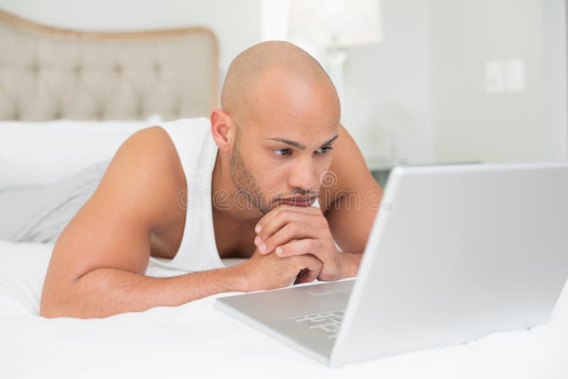 Serious Casual Bald Man Using Laptop in Bed Stock Photo - Image of ...