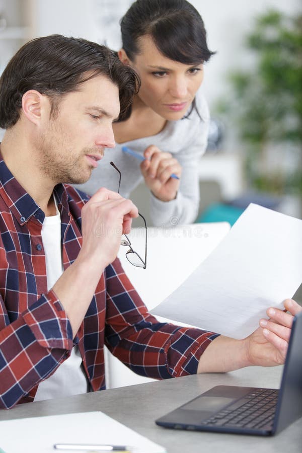 Serious Couple with Laptop Looking at Paperwork Stock Photo - Image of ...