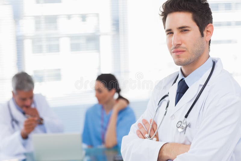 Serious Doctor Looking at Camera with Colleagues Behind Stock Image ...