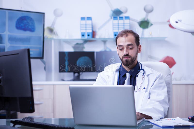 Serious Doctor Typing a Treatment on His Laptop Stock Photo - Image of ...