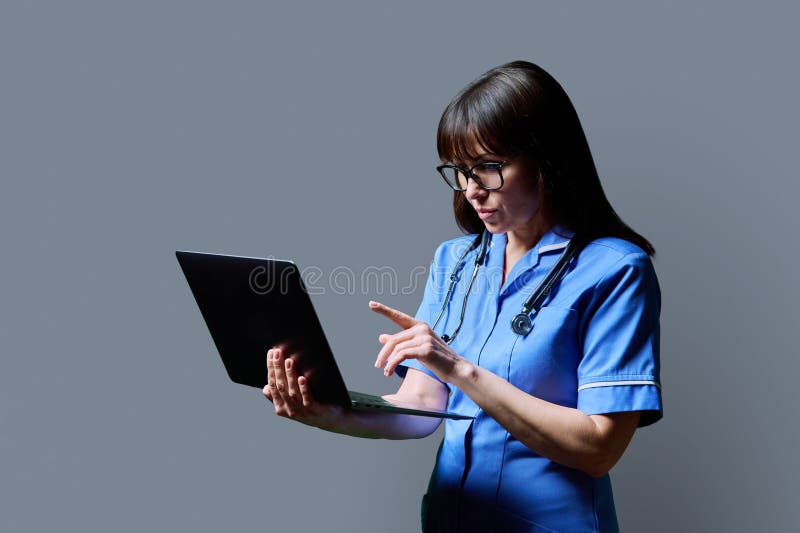Female Nurse Using Laptop, Profile View on Gray Studio Background Stock ...