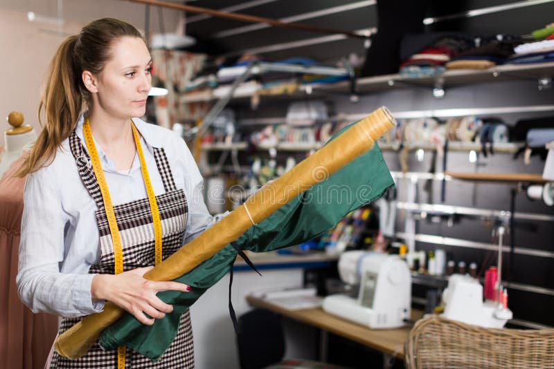 Serious Female Professional Sewer Holding Tubes with Material Stock ...