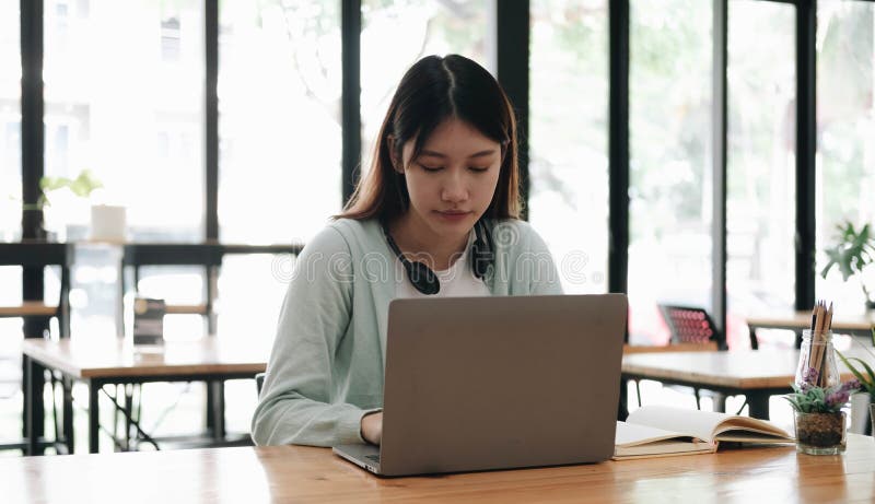 Serious Focused Asian Student Using Laptop in Kitchen, Looking at ...