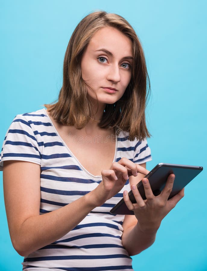 Young Girl Holding a Book in One Hand and a Tablet-pc in the Other ...